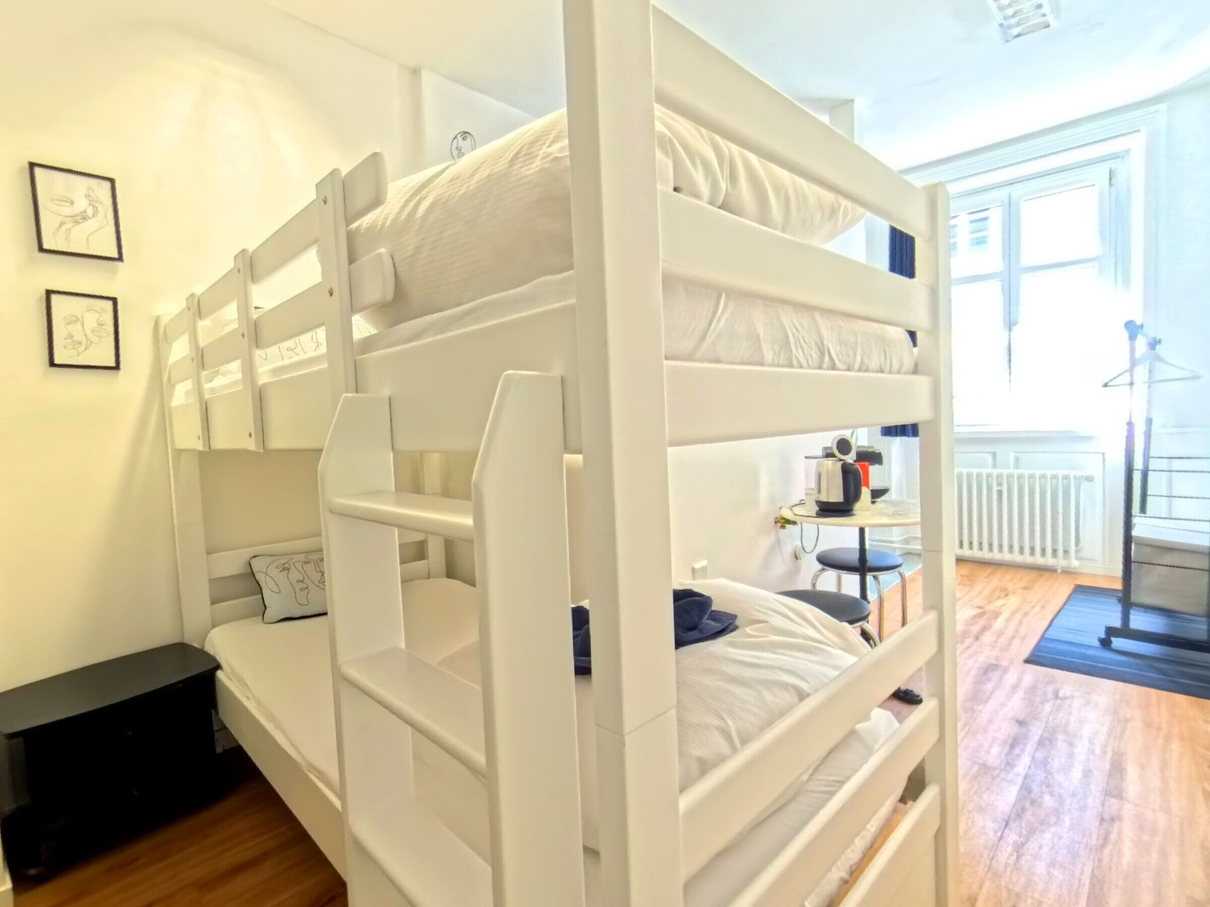 Quarto com beliche, escrivaninha, cadeira, radiador e janela.