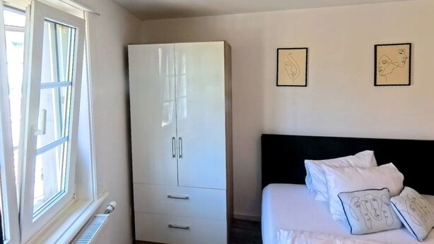 Quarto com cama, guarda-roupa e duas obras de arte na parede.