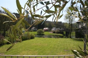 Um jardim bem cuidado com gramado, um pequeno lago e uma ponte.