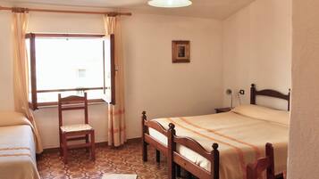 Quarto com cama, cadeira, mesa de cabeceira, luminária, janela com cortinas e um quadro na parede.