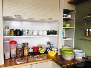 Uma cozinha com prateleiras contendo frascos, canecas e pratos.