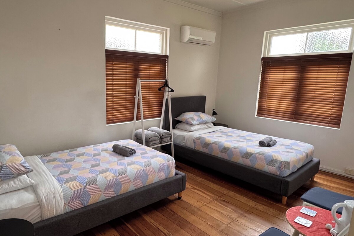 Quarto com duas camas de solteiro, uma mesinha e uma cadeira.