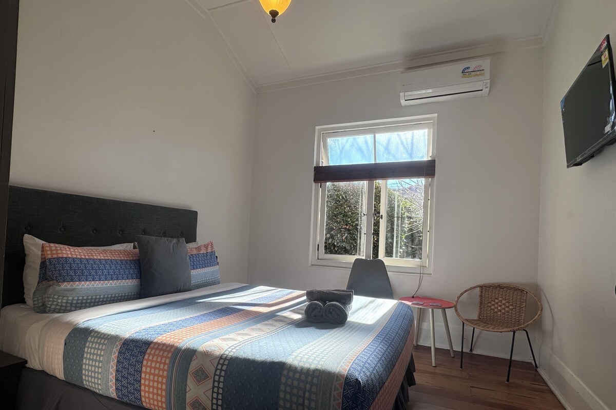 Quarto com cama, cadeira, janela e ar condicionado.