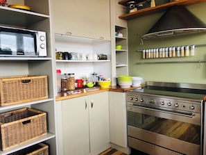 Cozinha equipada com micro-ondas, fogão e diversas estantes.