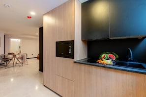 Uma cozinha moderna com armários de madeira, micro-ondas embutido e bancada preta.