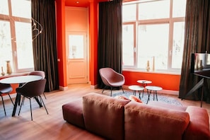 Uma sala de estar moderna com sofá, cadeiras, mesa de jantar e televisão.