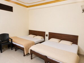 Quarto com duas camas de madeira, uma cadeira e luminária na parede.