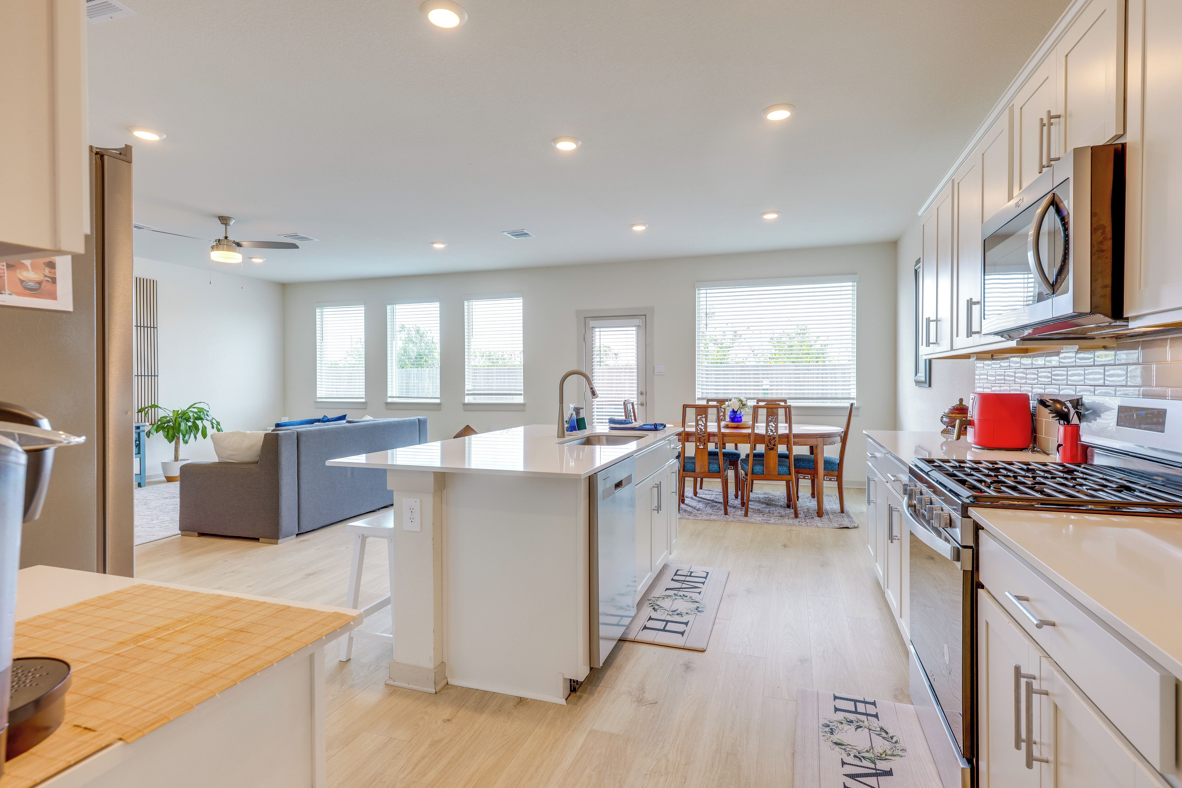 Uma cozinha moderna com uma ilha central, uma sala de jantar com mesa e cadeiras, e uma sala de estar com sofá.