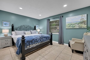 Quarto com cama, mesas de cabeceira, cómoda e um quadro na parede.
