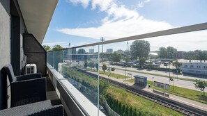 Varanda com vista para uma linha de trem e paisagem urbana.