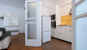 Uma cozinha moderna com armários brancos, uma geladeira de porta dupla e um forno embutido.
