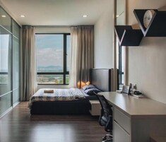 Quarto de hotel moderno com uma cama grande, escrivaninha, televisão e vista para a cidade.