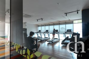Academia com esteiras, uma pessoa usando bicicleta ergométrica e uma criança em uma esteira.