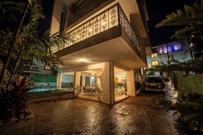 Um hotel com área de estar coberta ao ar livre, piscina e um carro estacionado na entrada.