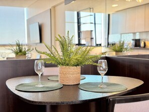 Mesa de jantar com duas taças de vinho e um arranjo de planta trançada.
