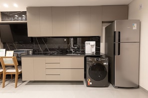 Uma cozinha moderna com máquina de lavar embutida, frigorífico e máquina de café.