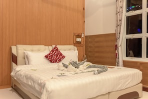 Quarto com cama, almofadas, mesa de cabeceira e janela com cortinas.
