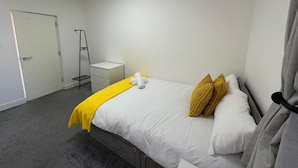 Quarto de hotel com cama, mesa de cabeceira, cadeira e guarda-roupa.