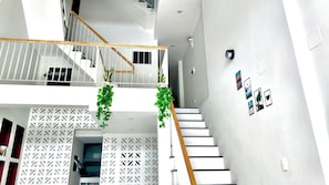 Um interior moderno com escada, paredes brancas e um detalhe decorativo na parede.