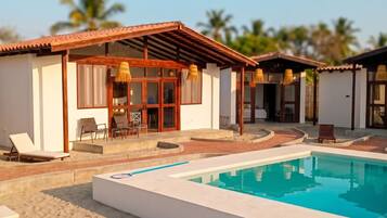 Um resort com piscina, espreguiçadeiras e área de estar coberta ao ar livre.