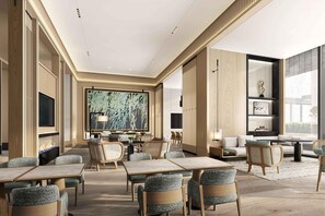 Um saguão moderno de hotel com uma grande pintura abstrata, assentos confortáveis e uma ampla janela com vista.
