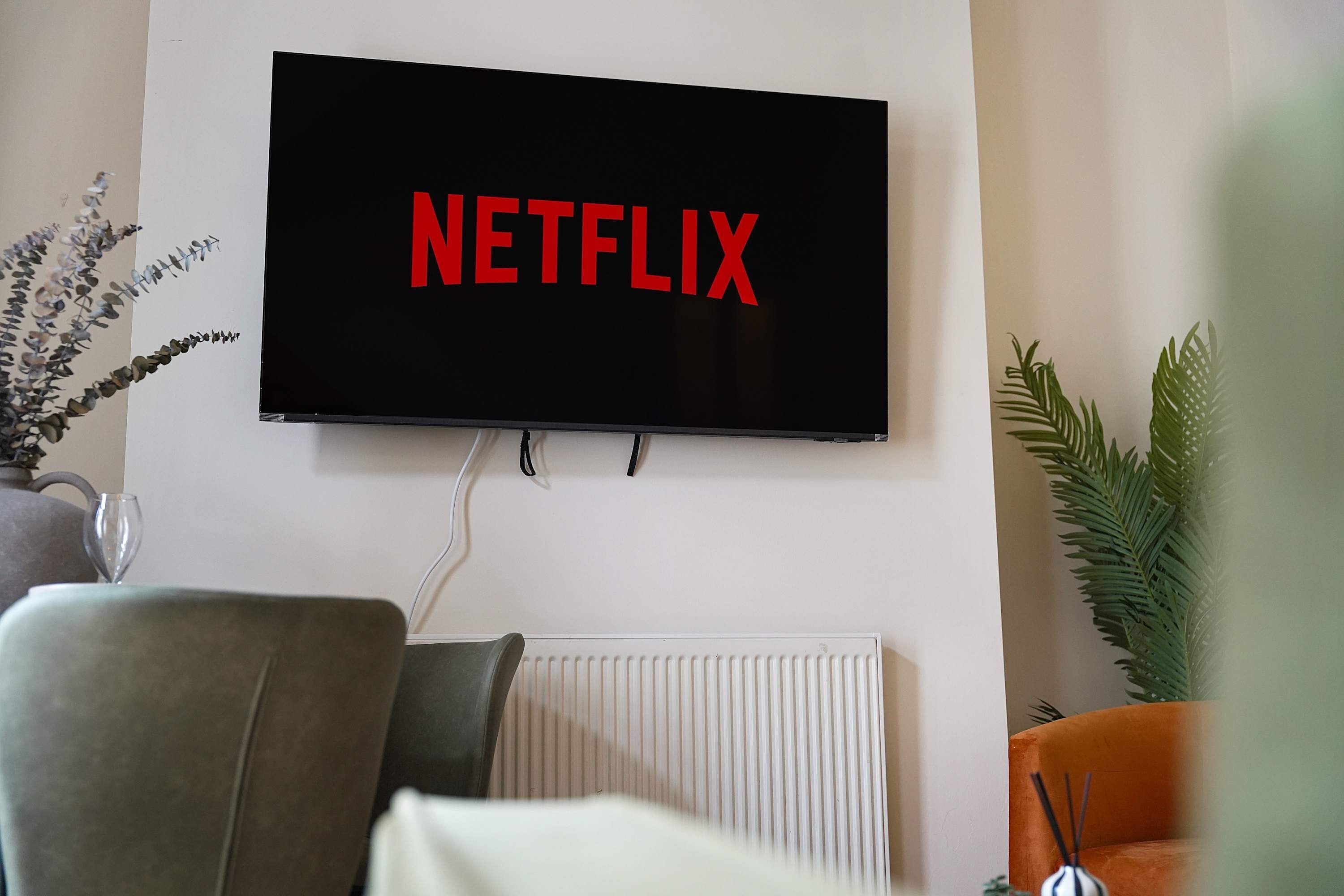 Uma televisão presa na parede exibindo o logotipo da Netflix.