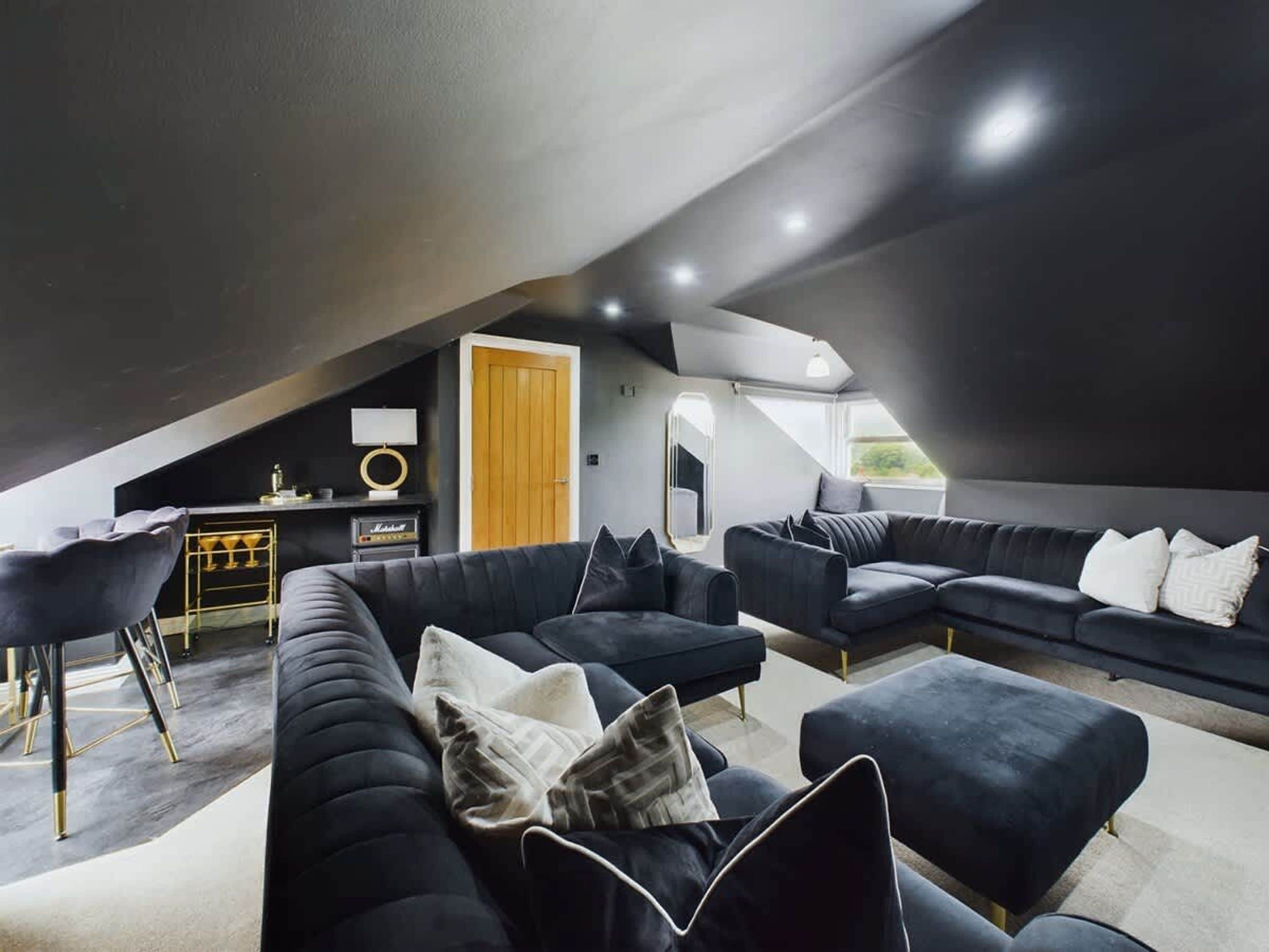 Um espaço de estar moderno estilo loft, com pé-direito alto, móveis em tons escuros e uma área de estar acolhedora.