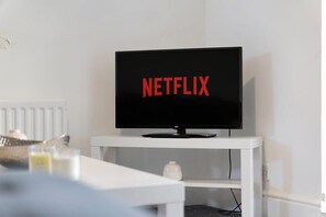 Uma televisão sobre um suporte branco com o logotipo da Netflix exibido na tela.