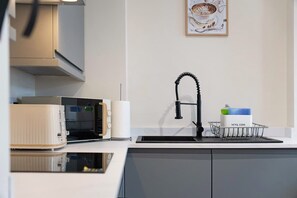 Cozinha moderna com micro-ondas, torradeira, pia e um quadro na parede.