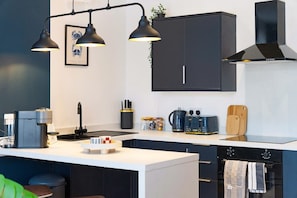 Uma cozinha moderna com ilha central, armários pretos e iluminação pendente.