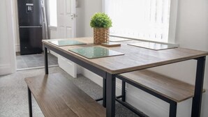 Uma cozinha com uma mesa de madeira, um banco e um vaso com planta.