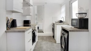 Uma cozinha moderna com armários brancos, forno embutido, micro-ondas e pia.