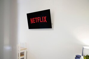 Uma televisão fixada na parede com a palavra 'NETFLIX' em letras vermelhas.