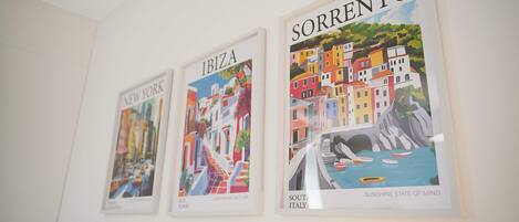 Três obras de arte emolduradas com os títulos 'NEW YORK', 'IBIZA' e 'Sorrento' numa parede branca.