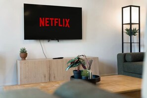 Uma sala de estar com uma TV de tela plana presa à parede exibindo o logotipo da Netflix.