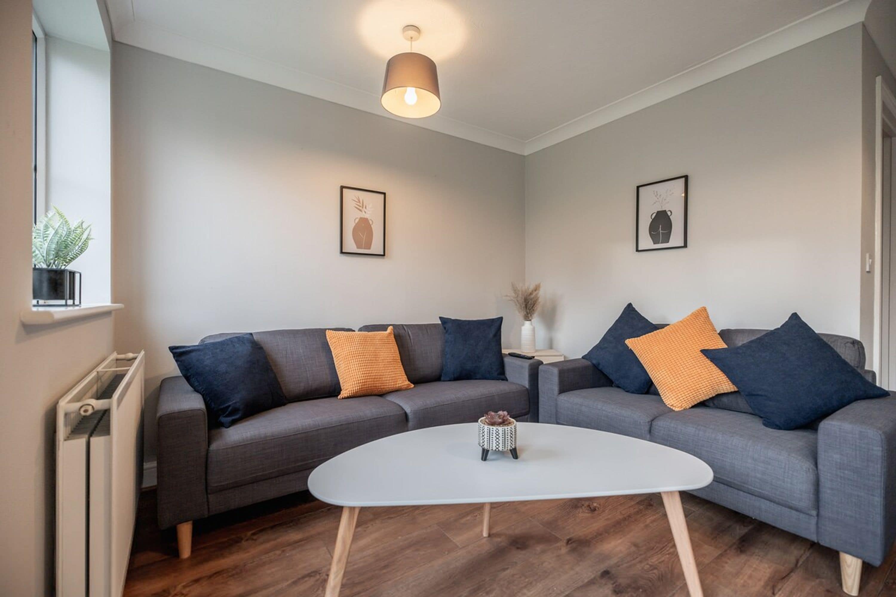 A modern living room with a grey sofa, white coffee table, and two wall-mounted light fixtures.
