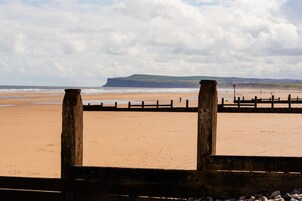 A beach with a wooden fence and a cliff in the background.