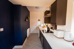 A modern kitchen with a herringbone floor, dark cabinetry, and a white countertop.