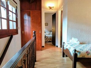 Quarto com cama de madeira, mesa de cabeceira e janela com cortinas.
