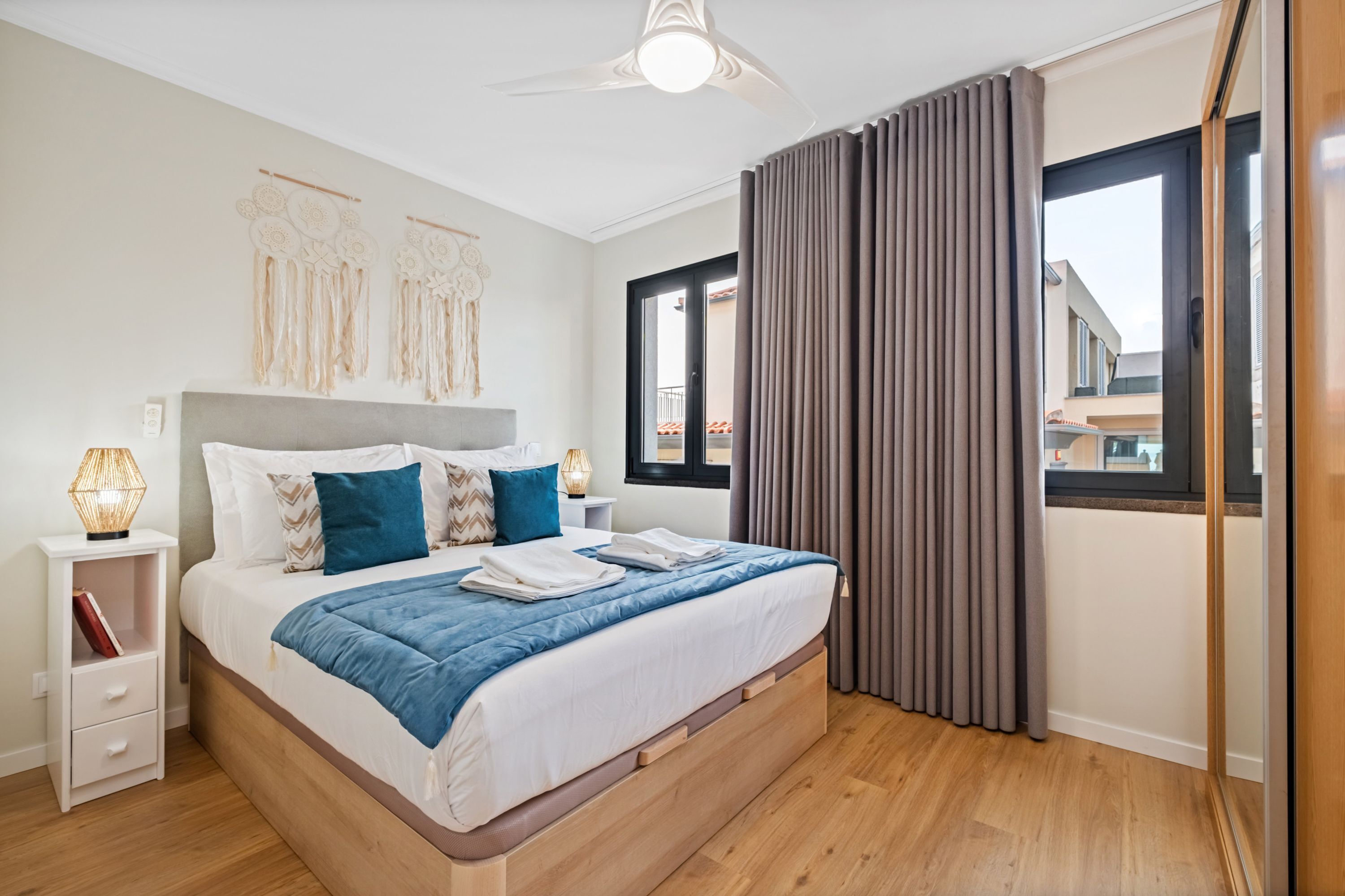 Quarto moderno com uma cama grande, abajures e vista para o exterior.