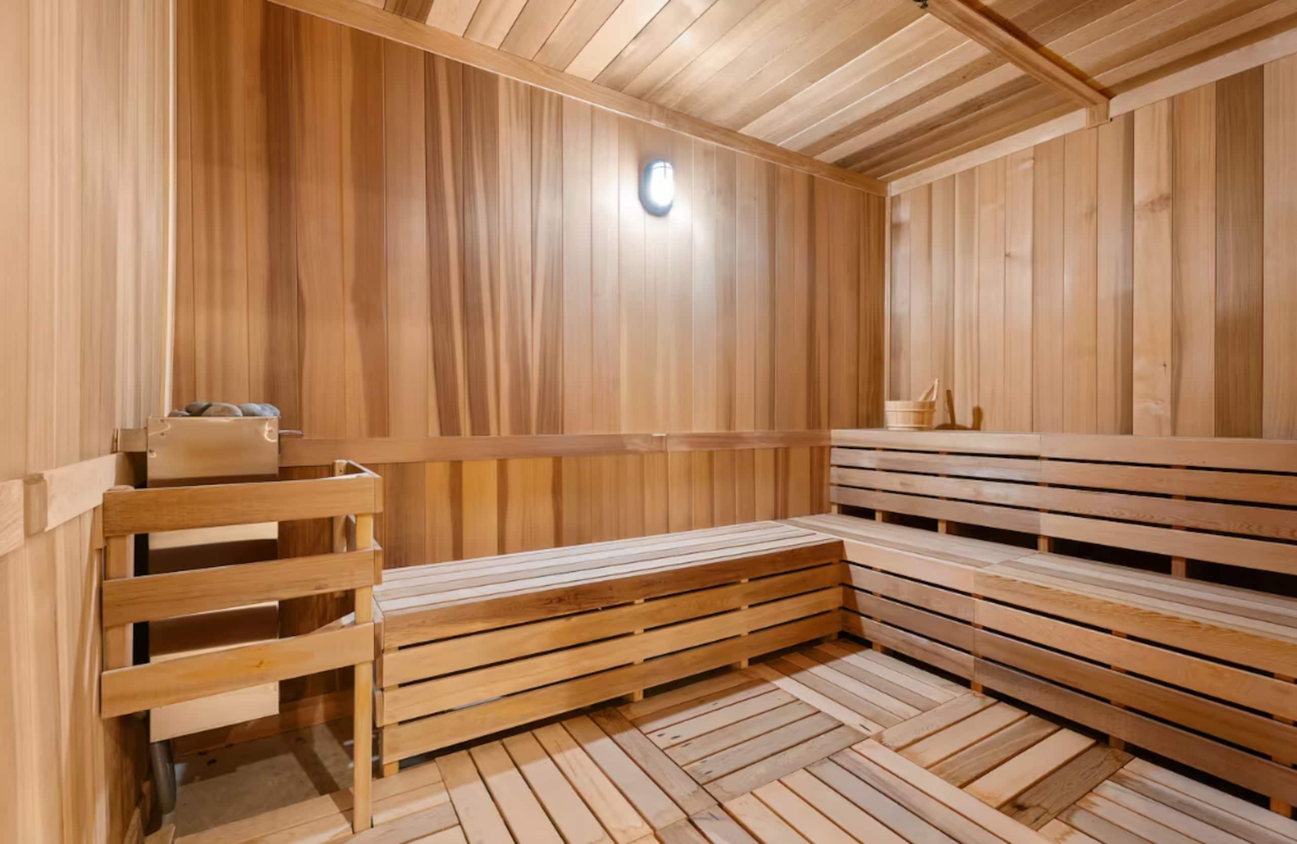 Uma sauna com bancos de madeira e um banco com toalha e bolsa.