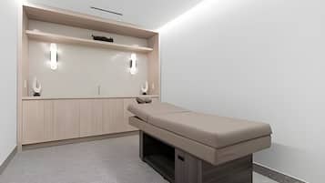Sala de exames médicos com uma mesa de exame individual, armários de madeira e dois armários fixos na parede com painéis iluminados.
