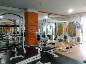 Uma academia com diversos equipamentos de exercício, incluindo máquinas de musculação e pesos livres.