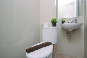 Casa de banho com sanita, lavatório e duas plantas em vasos.