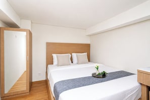 Quarto de hotel com cama, mesa de cabeceira e espelho.
