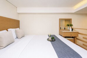 Quarto de hotel com uma cama, mesa de cabeceira com espelho e uma pequena planta na mesa.