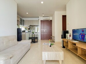 Uma sala de estar moderna com sofá, mesa de centro, televisão e cozinha ao fundo.