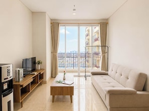 Uma sala de estar moderna com sofá, mesa de centro, TV e varanda com vista para a cidade.