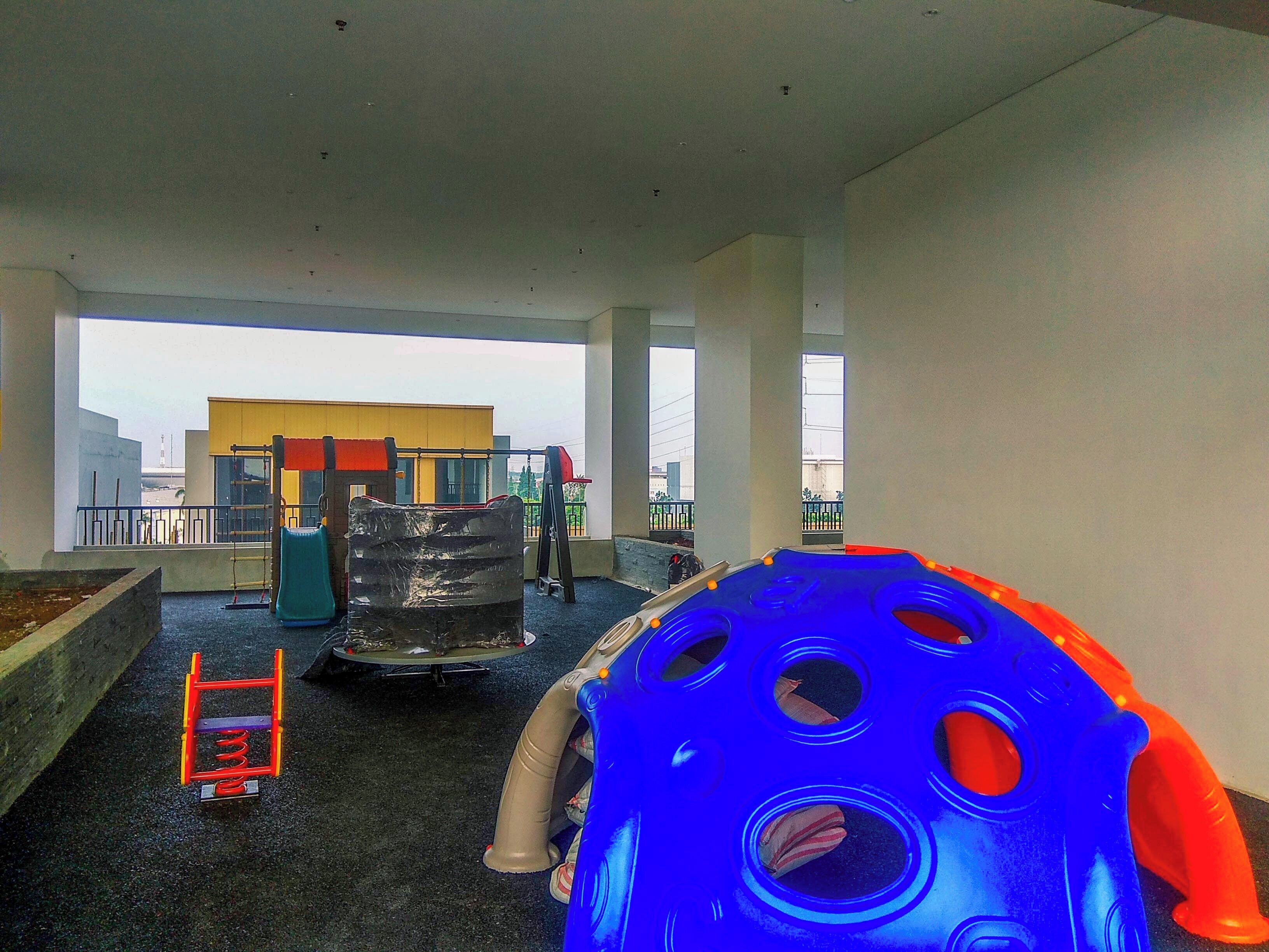 Área de recreação com escorregador, estrutura de escalada e piscina de bolinhas azul e laranja.
