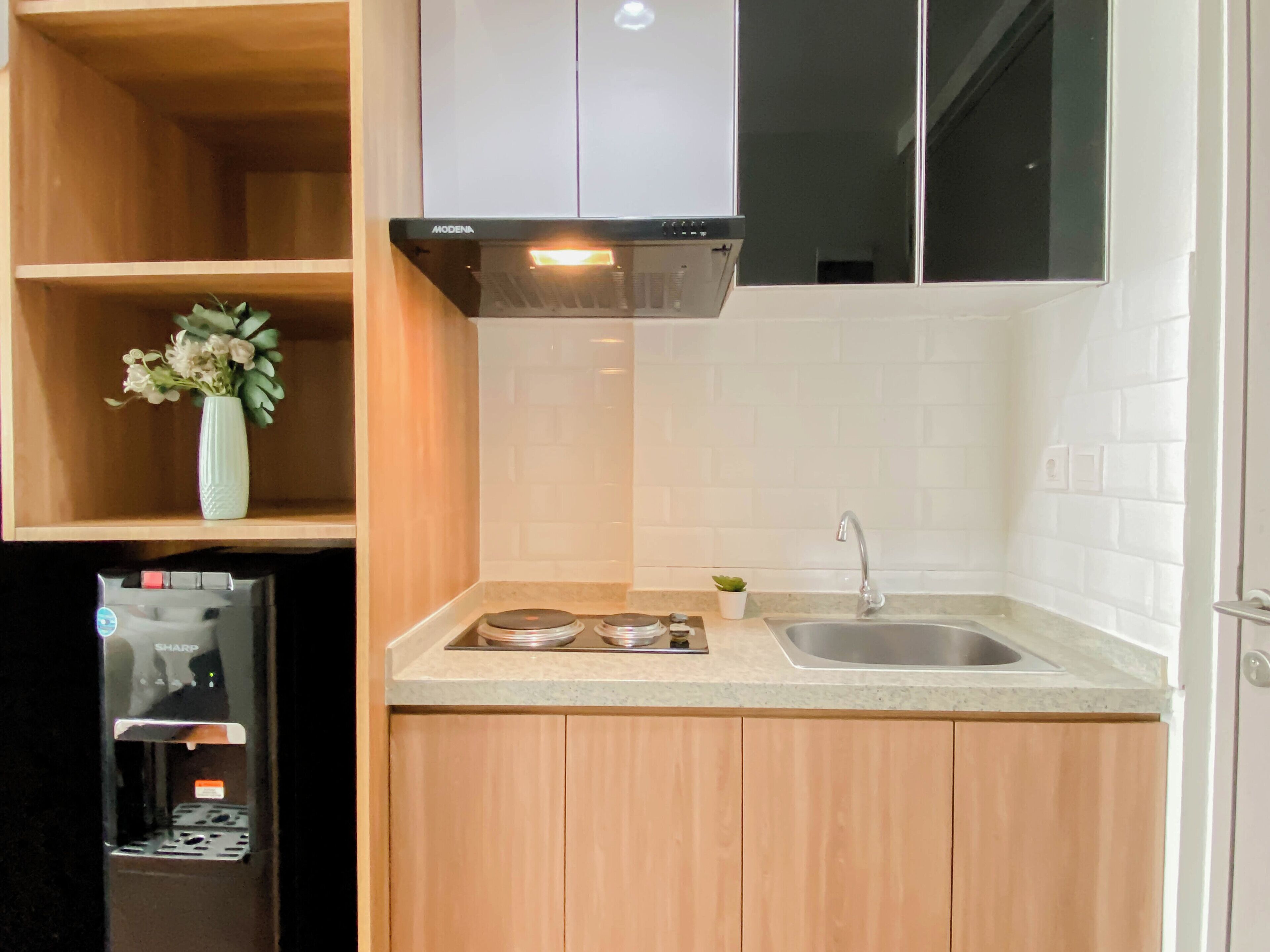 Cozinha com armários de madeira, pia de aço inoxidável e dispenser de água.